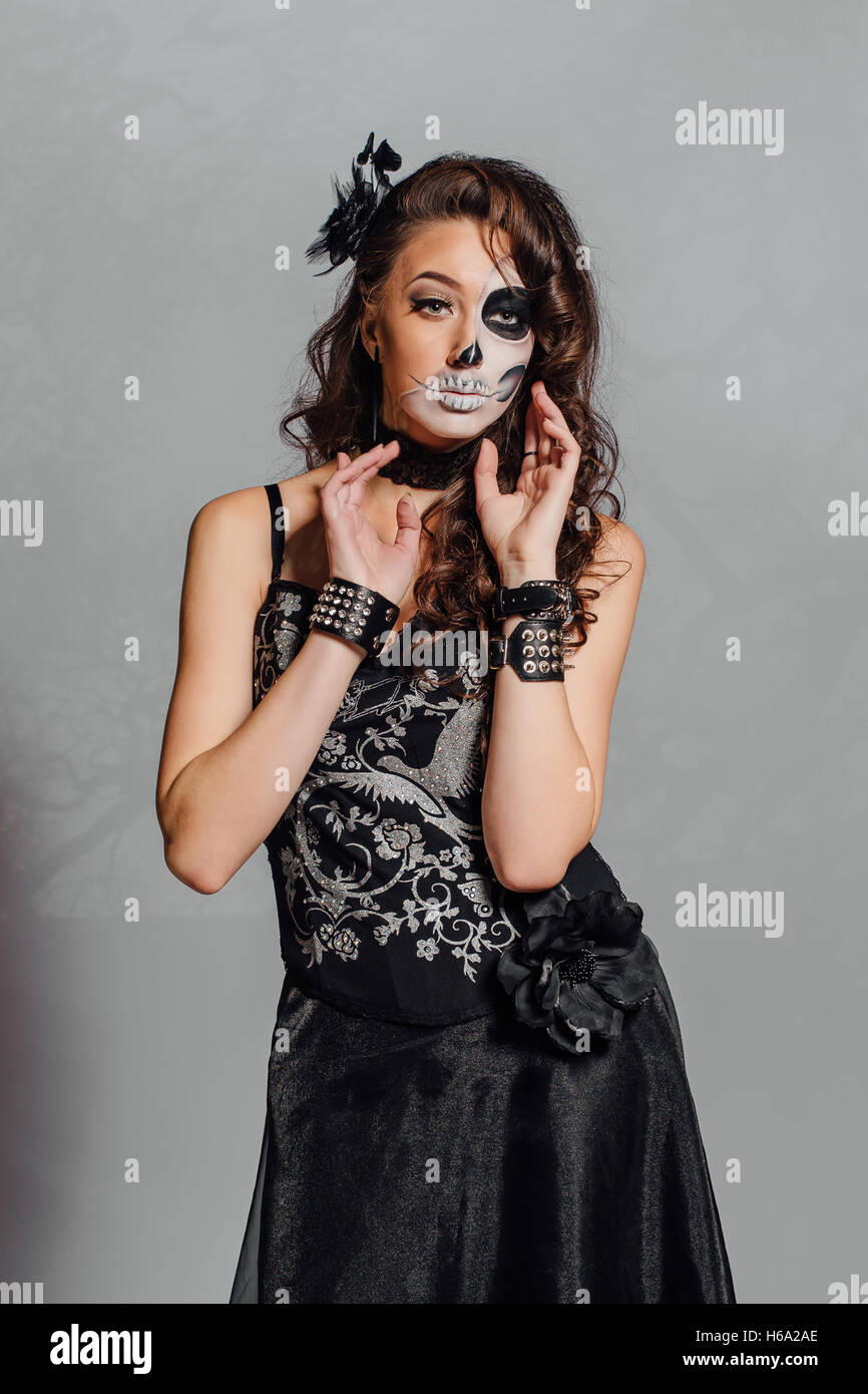 Young woman in black with half face skull make-up Stock Photo - Alamy