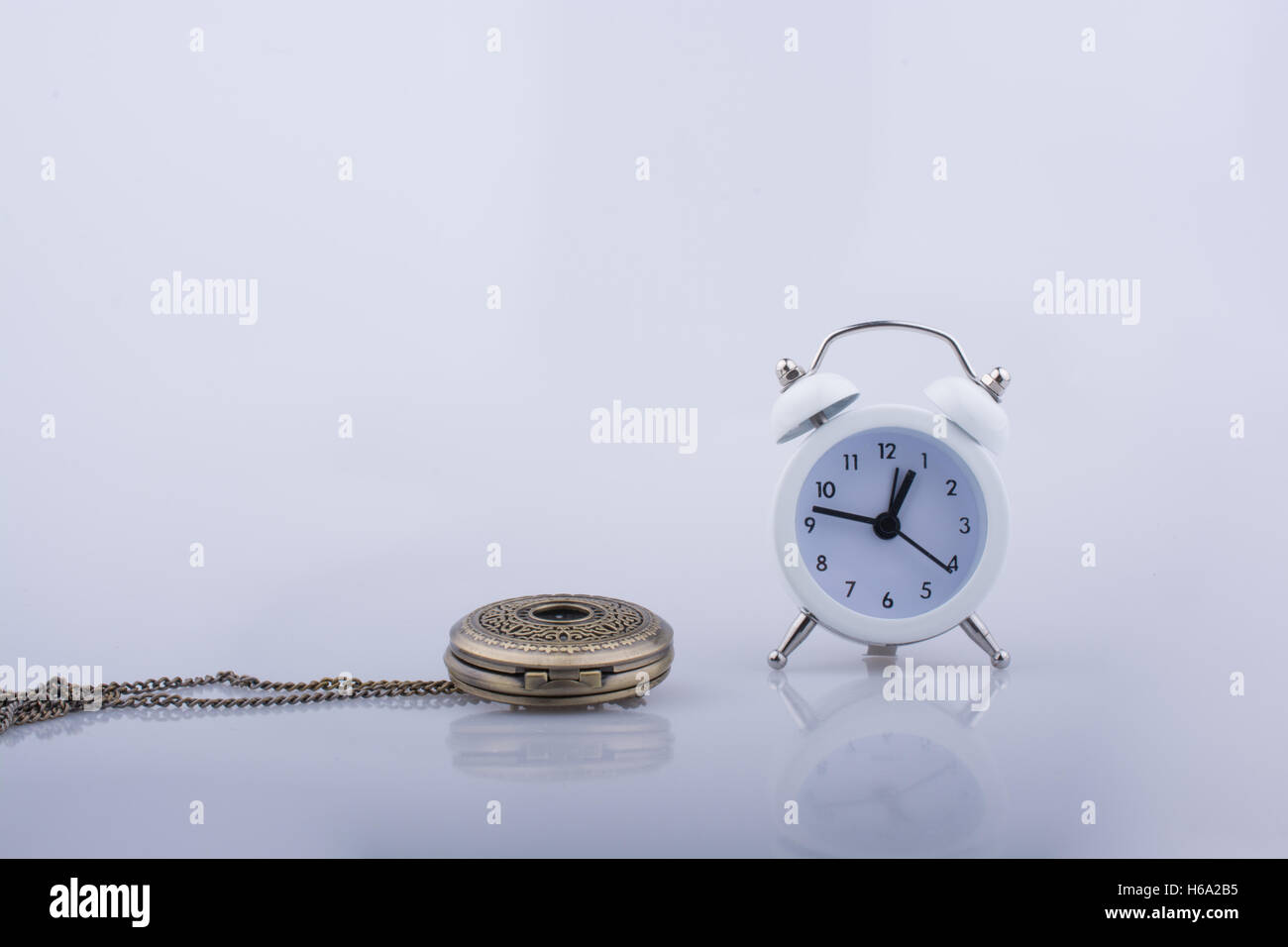 Alarm clock and a pocket watch side by side on white background Stock ...