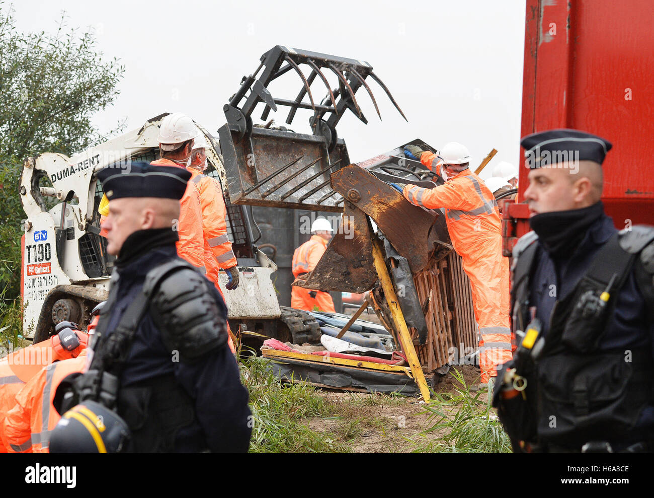 French police officers stand guard as a large crew of demolition ...