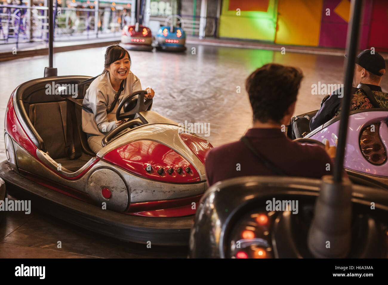Friends having fun on bumper car ride in amusement park. Young man and ...
