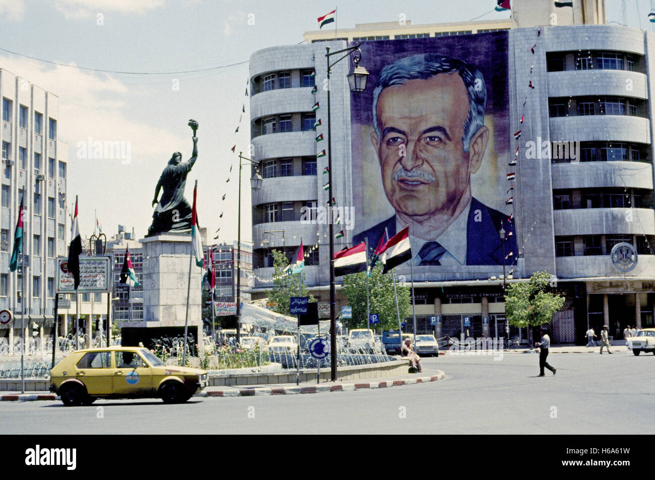 Several stories high, a fabric hanging depicts the Syrian President ...