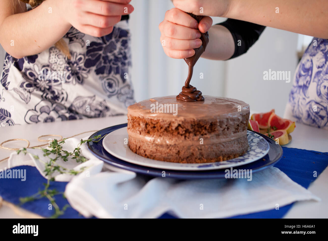 Two girls making a cake on the kitchen. Female hand squeezes the ...