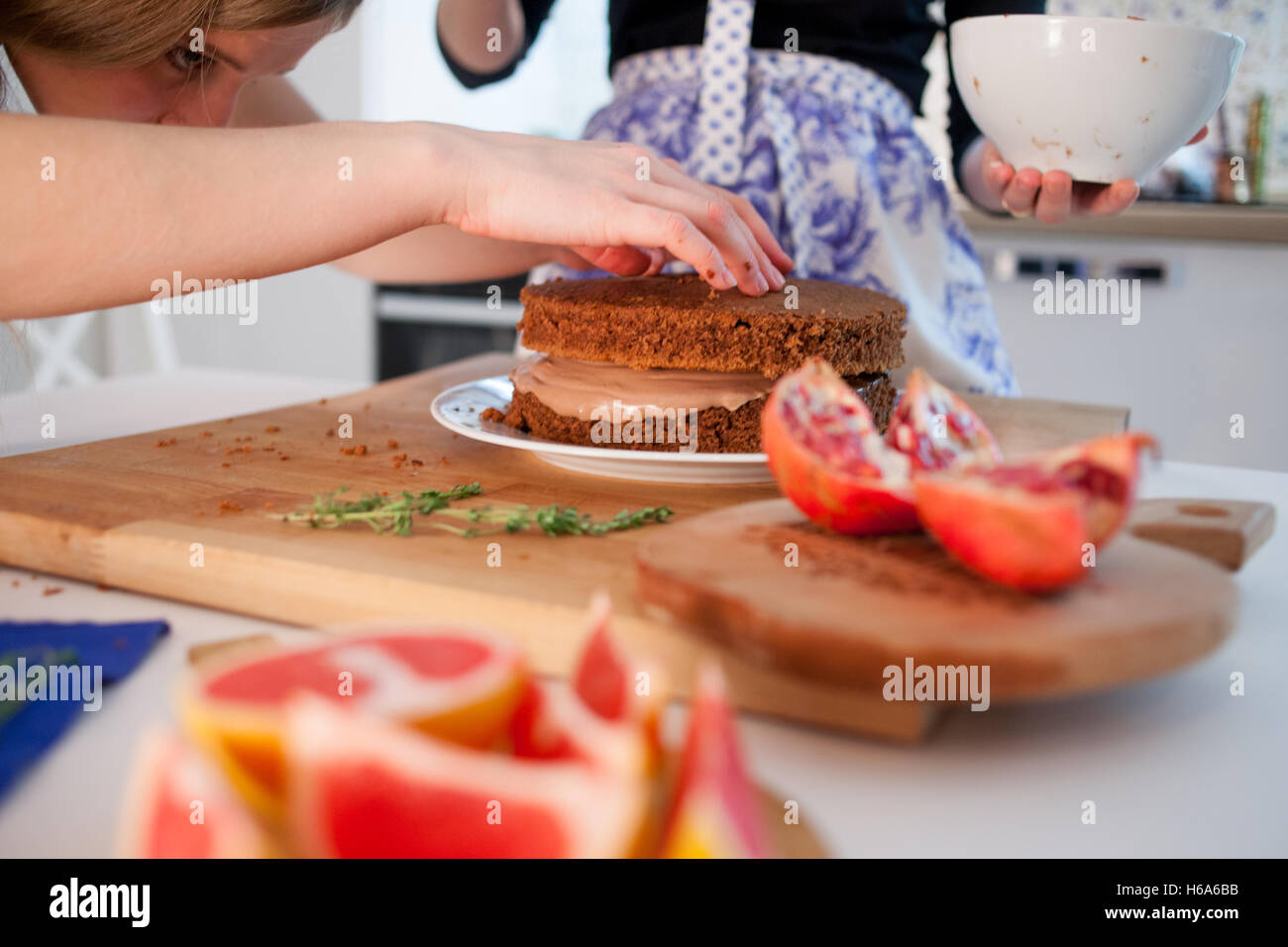 Two girls making a cake on the kitchen. Women's hands, causing the ...
