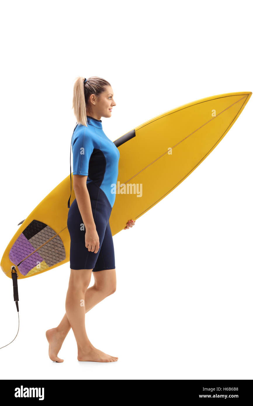 Full length profile shot of a female surfer walking and holding a ...