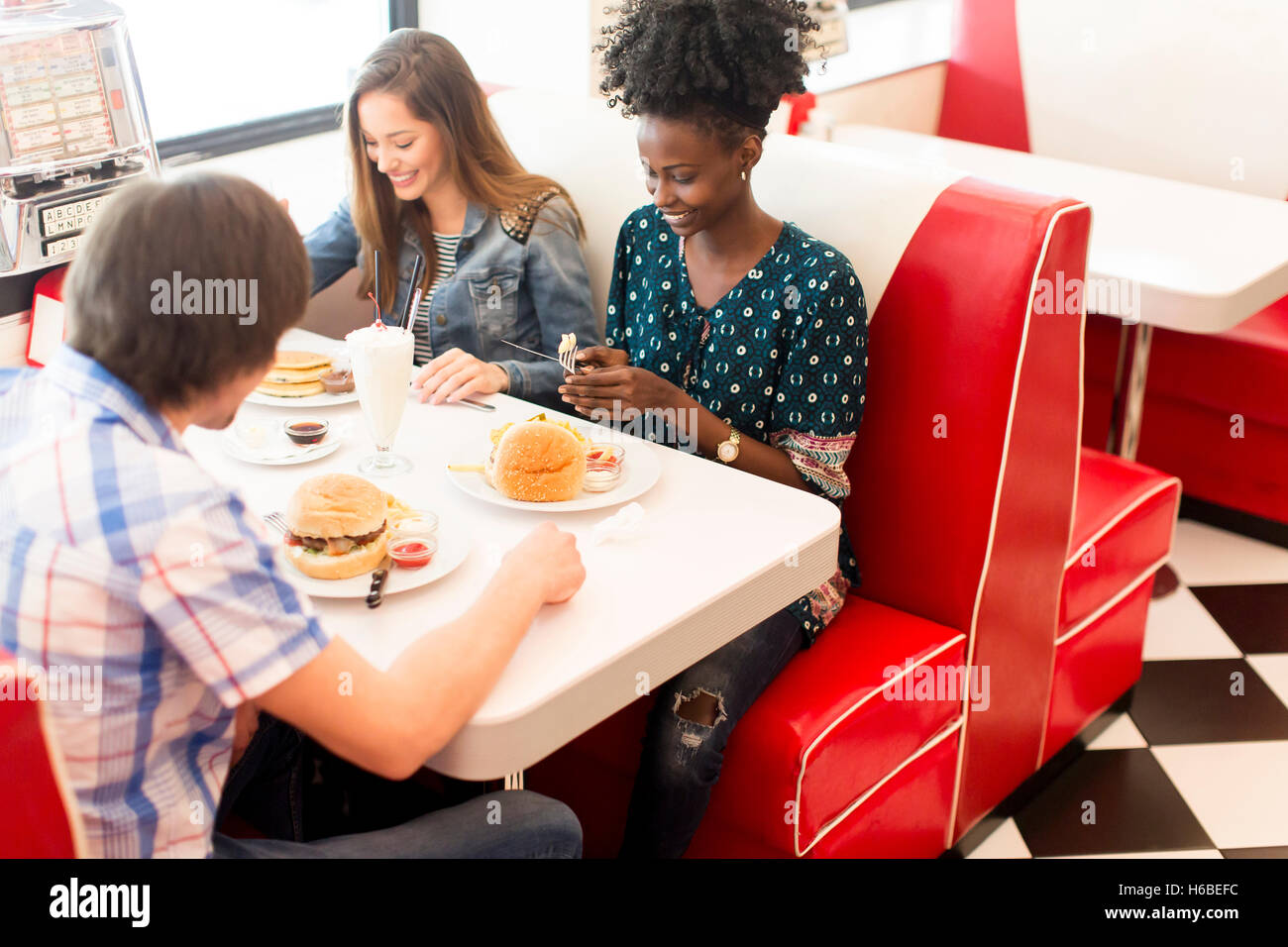 Friends eating fast food at the table in the diner Stock Photo - Alamy