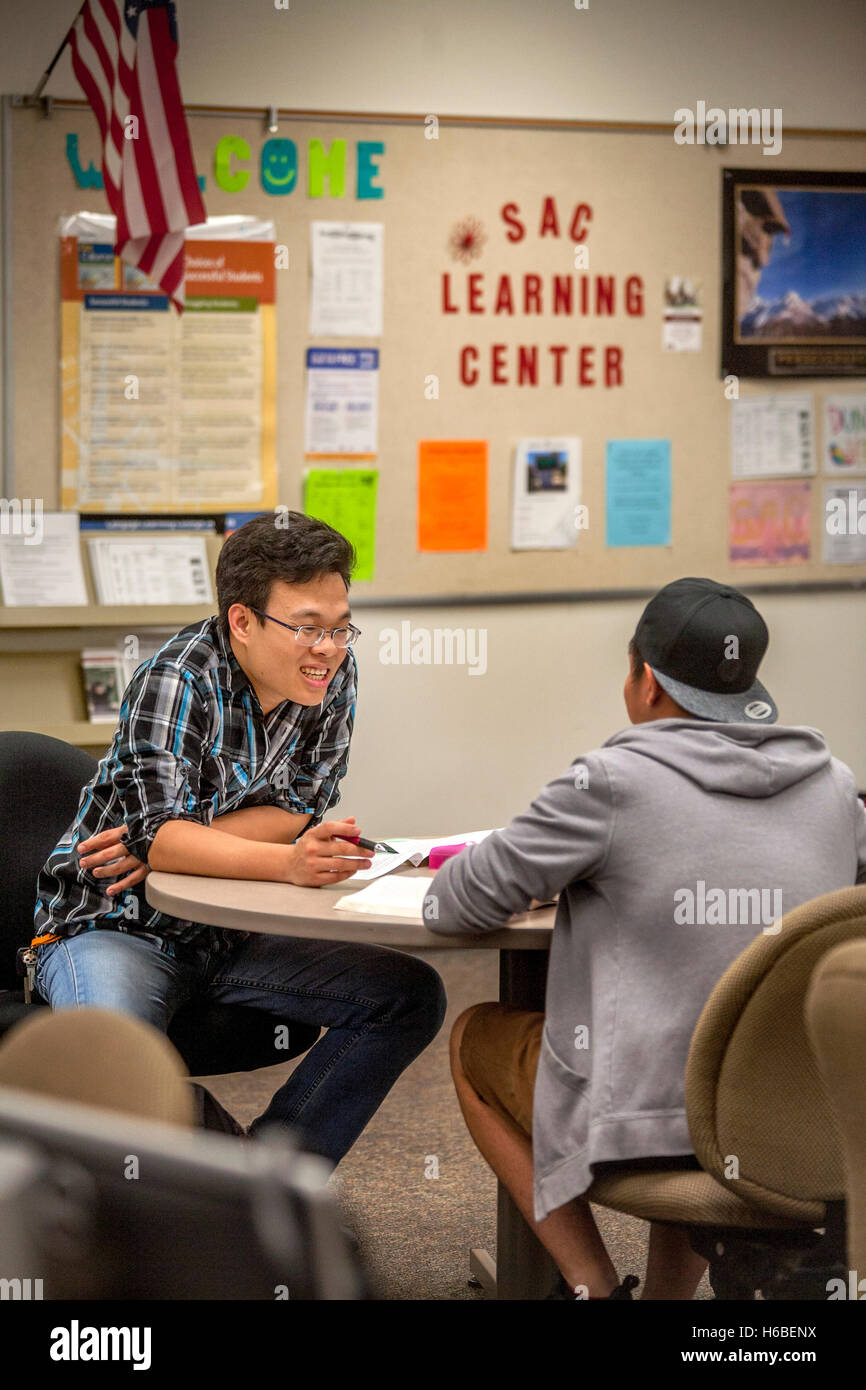 An Asian American tutor assists a Hispanic student in the learning ...