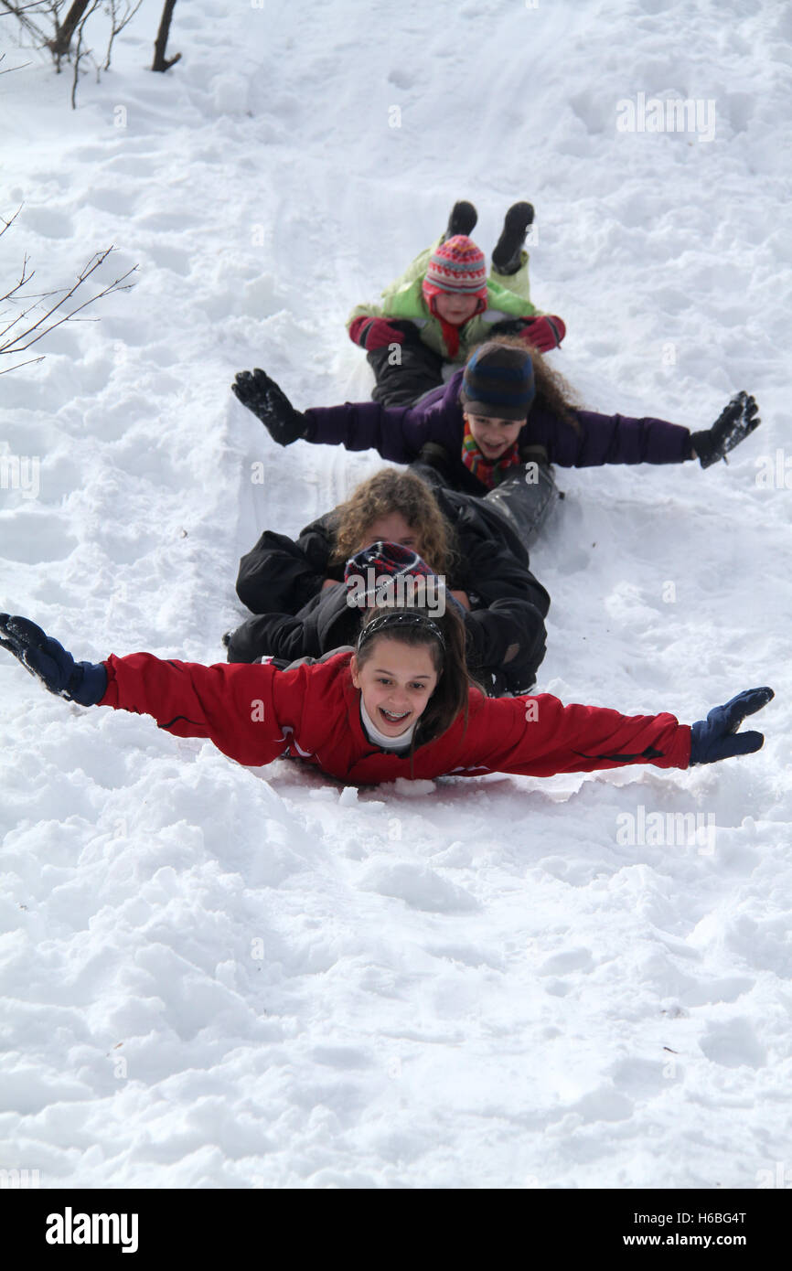 Group of children sliding down on snow Stock Photo - Alamy
