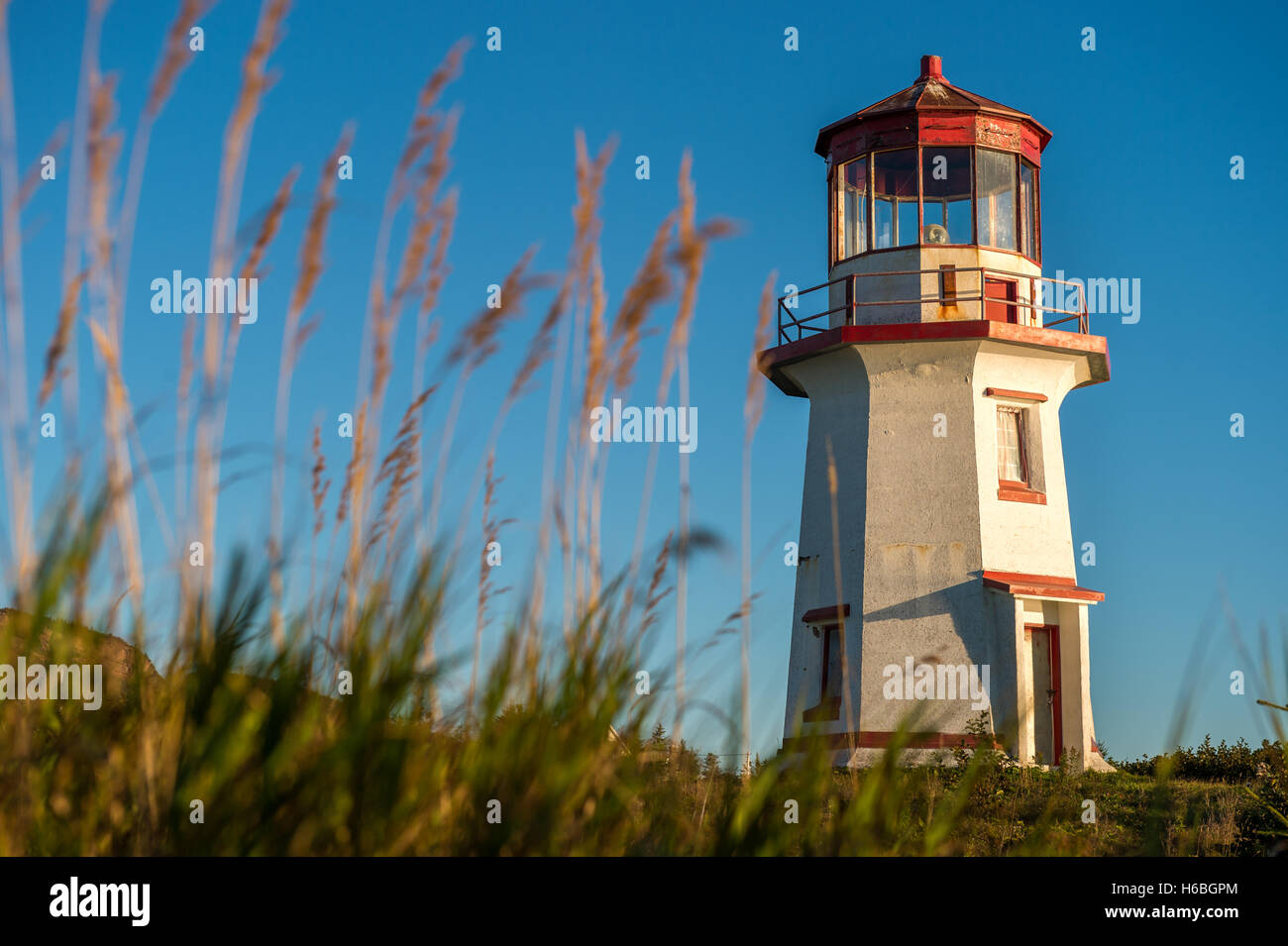 Red and white old lighthouse over blue sky in Gaspesie, Quebec (Percé ...