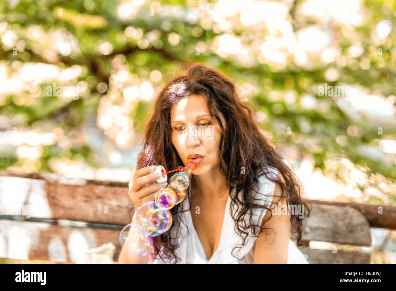 Beautiful Mature Adult Woman Playing In The Park Blowing Soap Bubbles