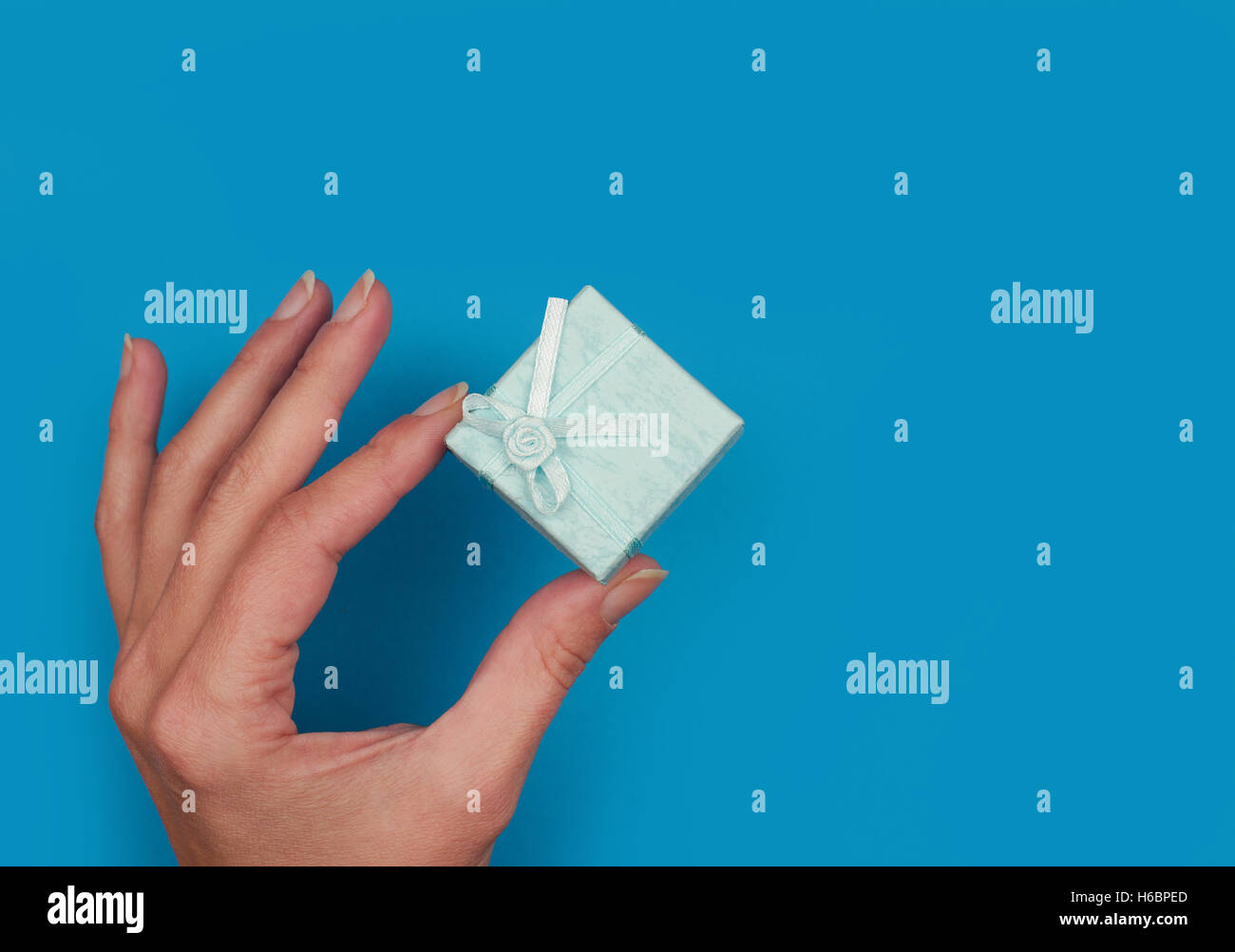 horizontal top view of hand holding with fingers one blue gift box blue ...
