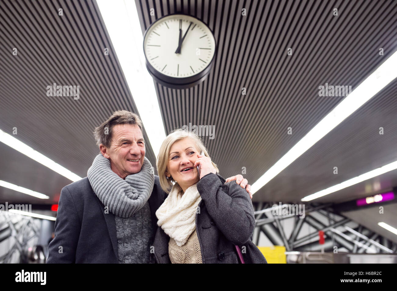 Senior couple standing at the underground platform, calling Stock Photo ...