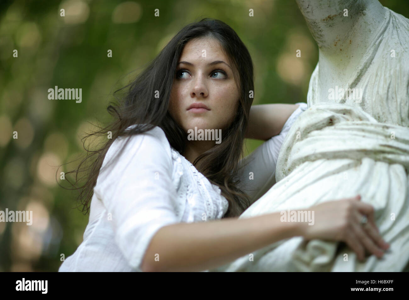 Young woman leaning against a statue Stock Photo - Alamy