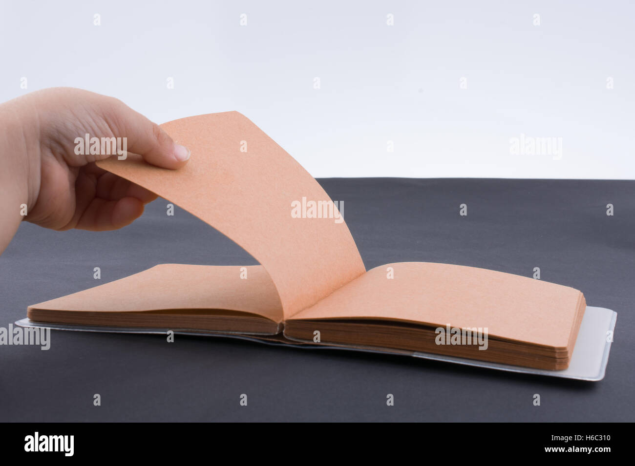 Hand holding brown color notebook on a white background Stock Photo - Alamy
