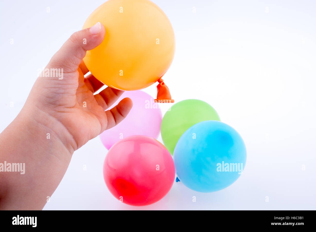 Hand holding a Colorful small balloon with colorful balloons on the ...
