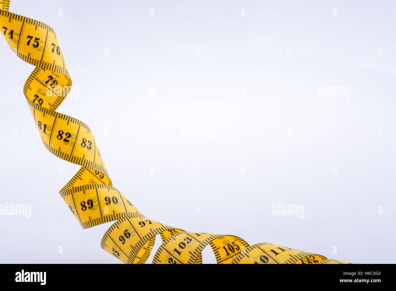 Yellow color measuring tape on a white background Stock Photo - Alamy