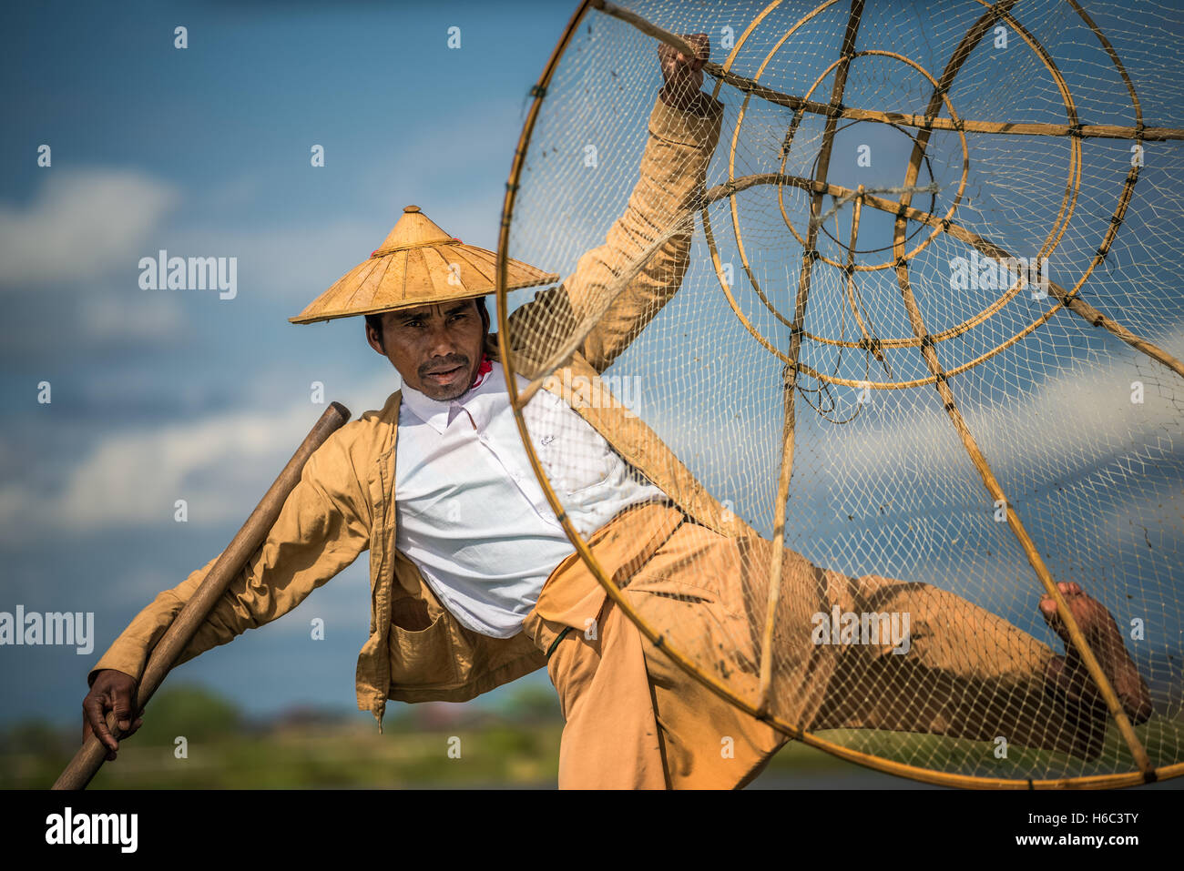 Close up of a burmese fisherman on a traditional bamboo boat using a ...