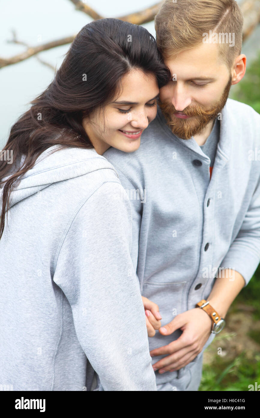 Young loving couple relaxing and hugging, she is smiling and leaning on ...
