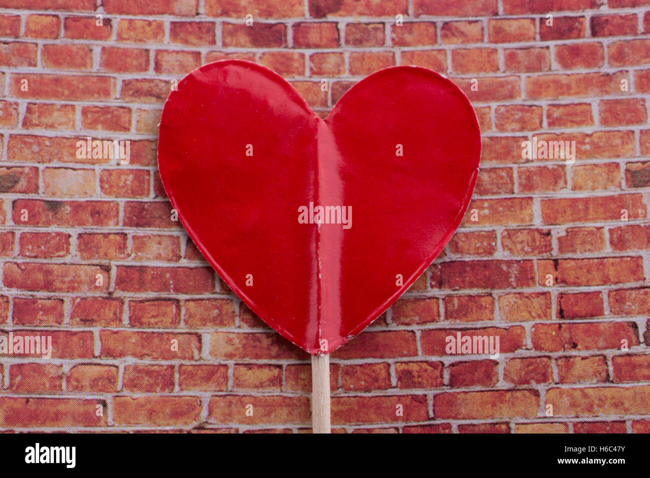 Red heart shape icon on a brick wall Stock Photo - Alamy