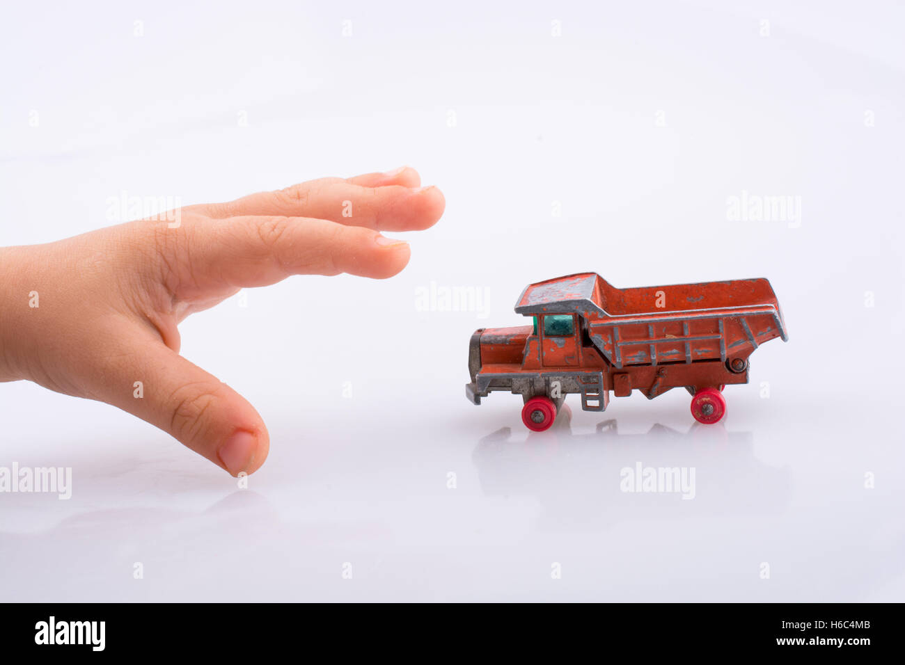 Baby hand is about to grab a red toy truck on white background Stock ...