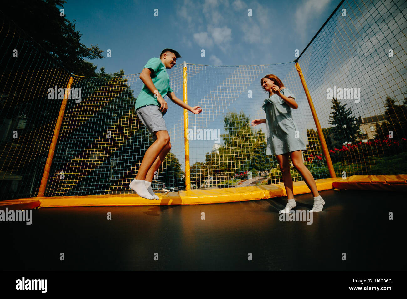 Couple jumping on trampoline in the park Stock Photo - Alamy