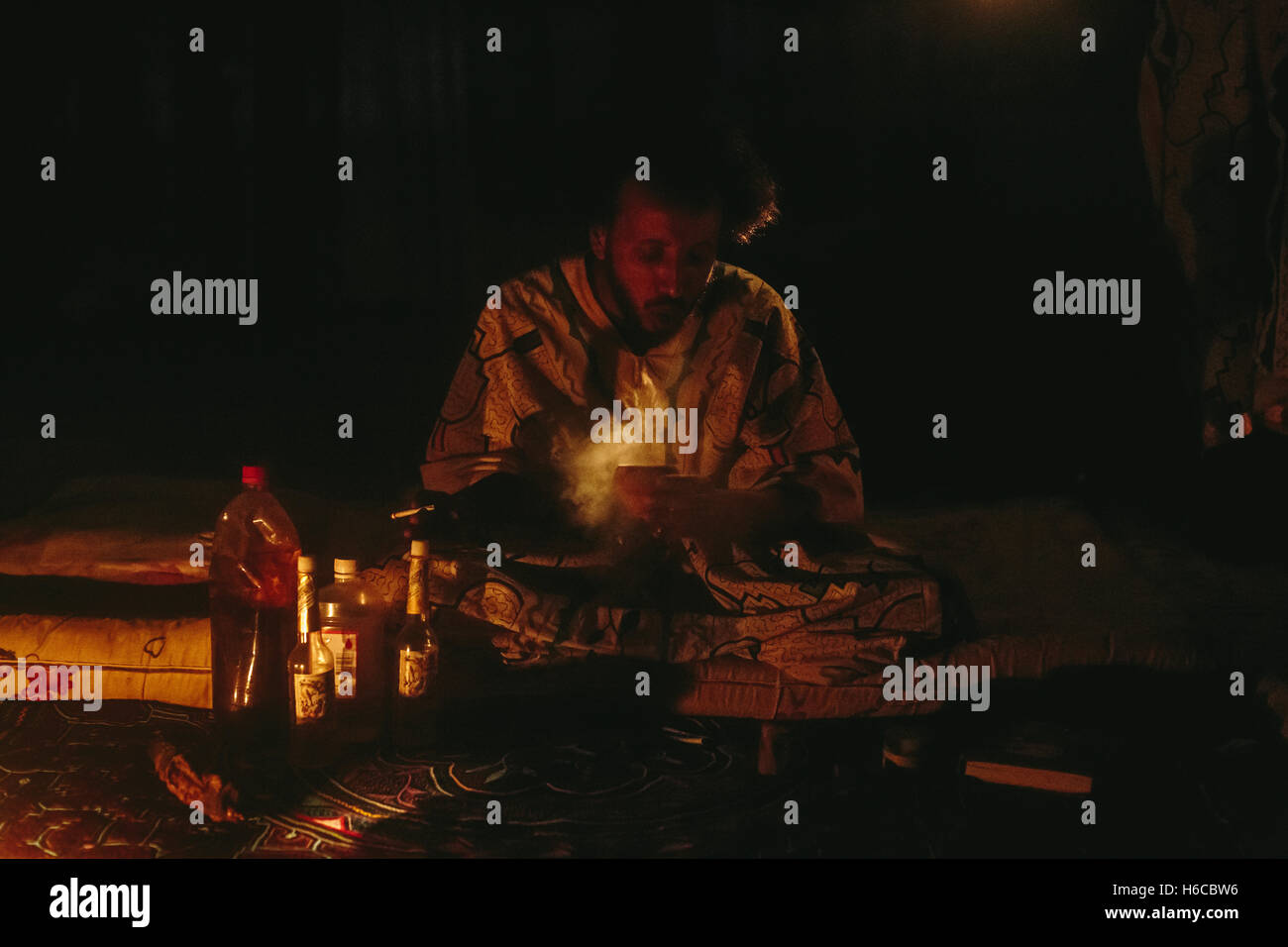 A shaman blows tobacco smoke over a cup of Ayahuasca, traditional ...