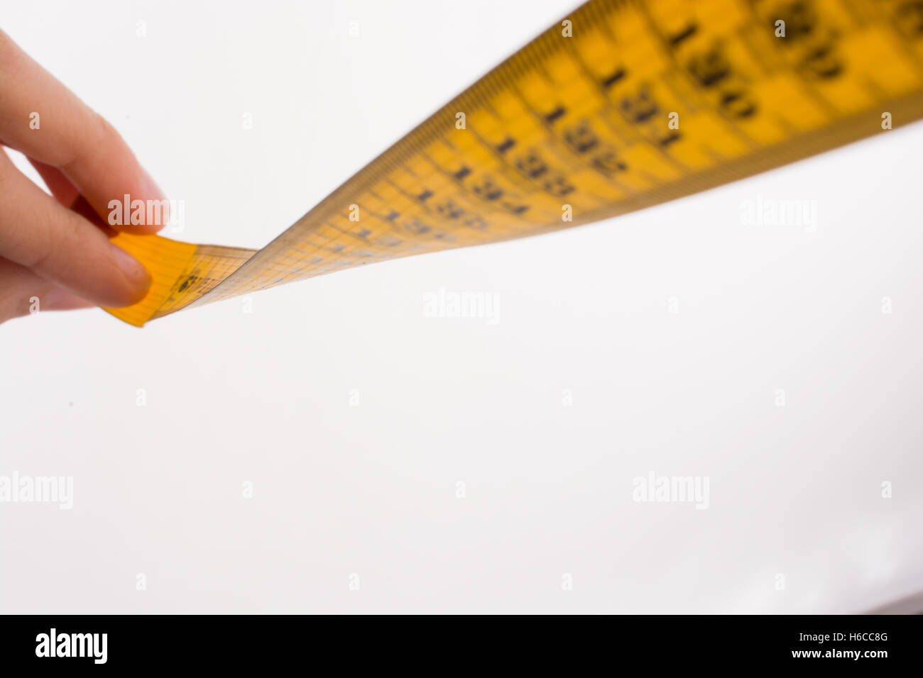 Hand holding a yellow color measuring tape on a white background Stock ...