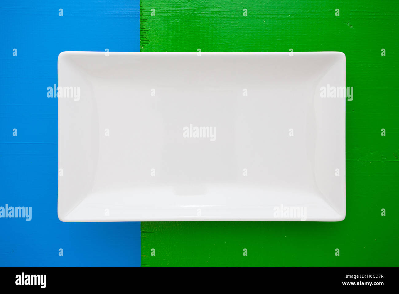 Empty white ceramic dish on over blue and green wooden table,rectangle ...