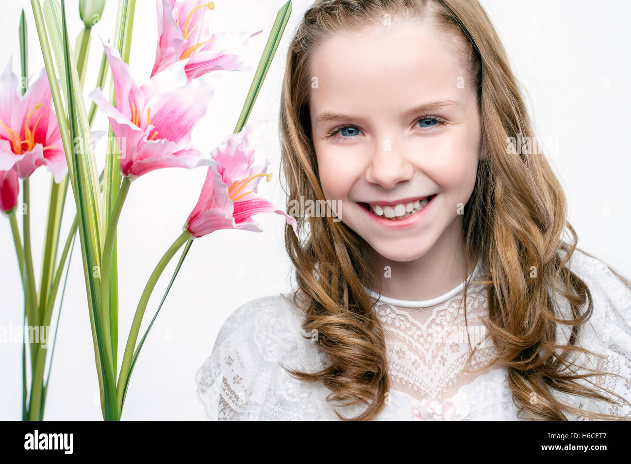 Close up studio beauty portrait of cute communion girl with flowers ...