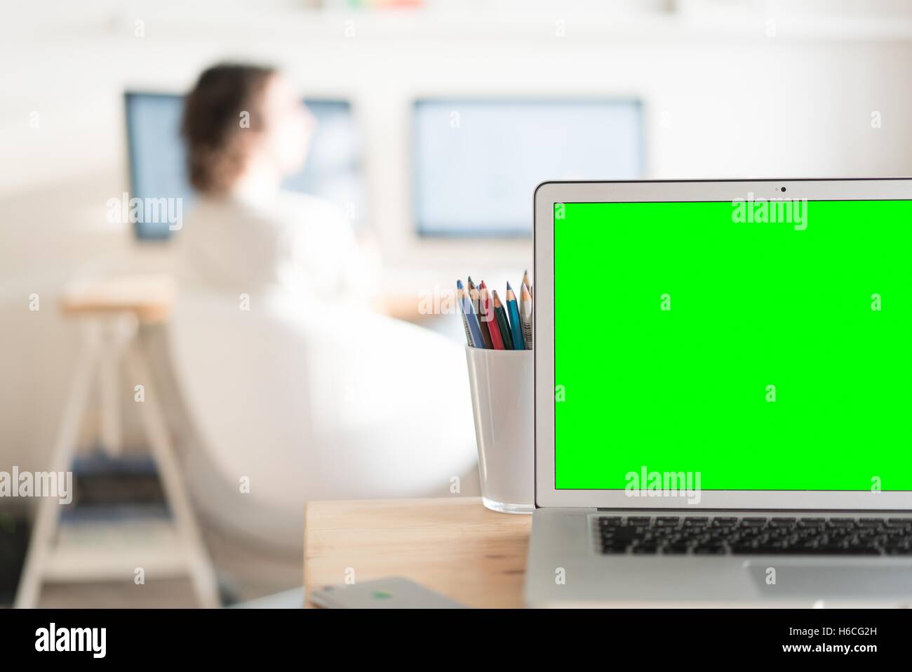 Green screen laptop computer and a glass with color pencils on wooden ...