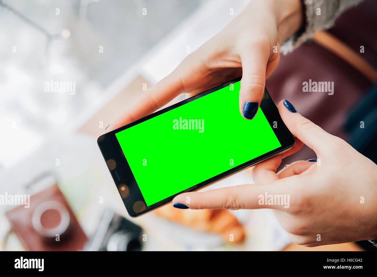 Modern phone with curved corners and green screen mock up held by woman ...