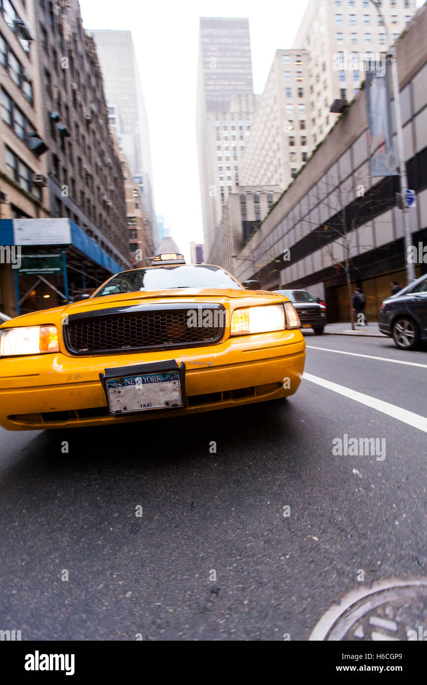 Wide and low angle view of a yellow taxi in a Midtown Manhattan street ...