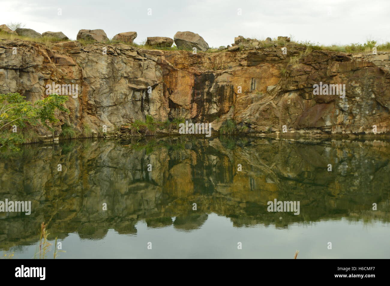 Rock wall reflected in lake water Stock Photo - Alamy