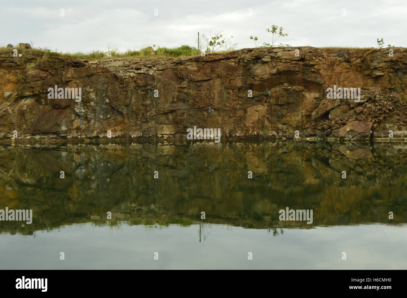 Rock wall reflected in lake water Stock Photo - Alamy