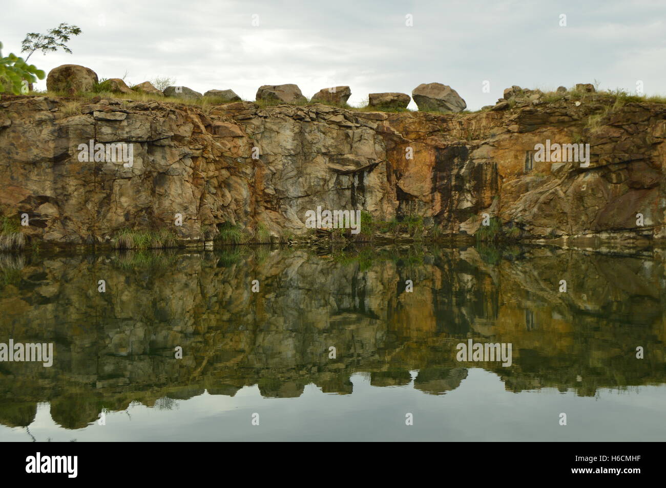 Rock wall reflected in lake water Stock Photo - Alamy