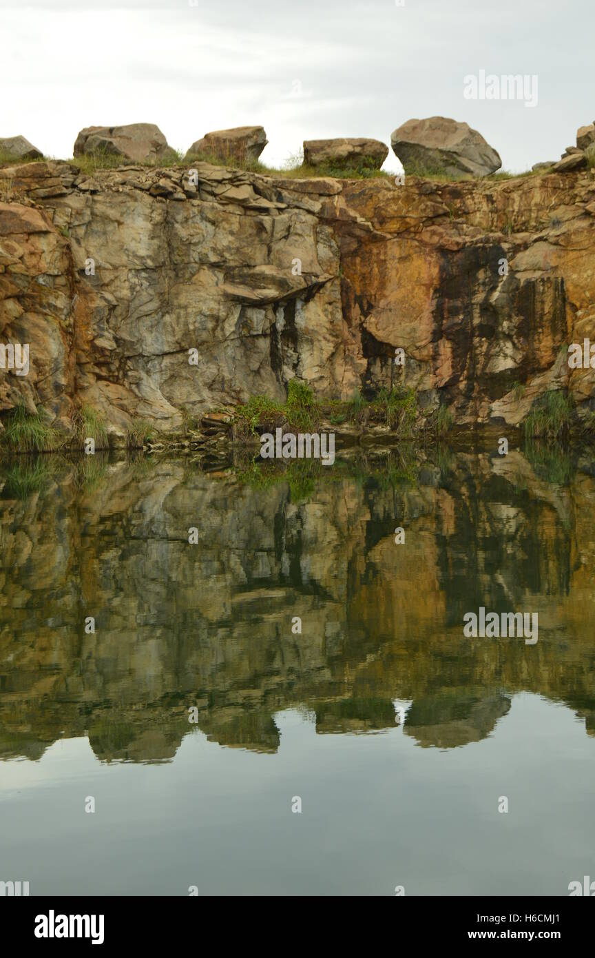Rock wall reflected in lake water Stock Photo - Alamy
