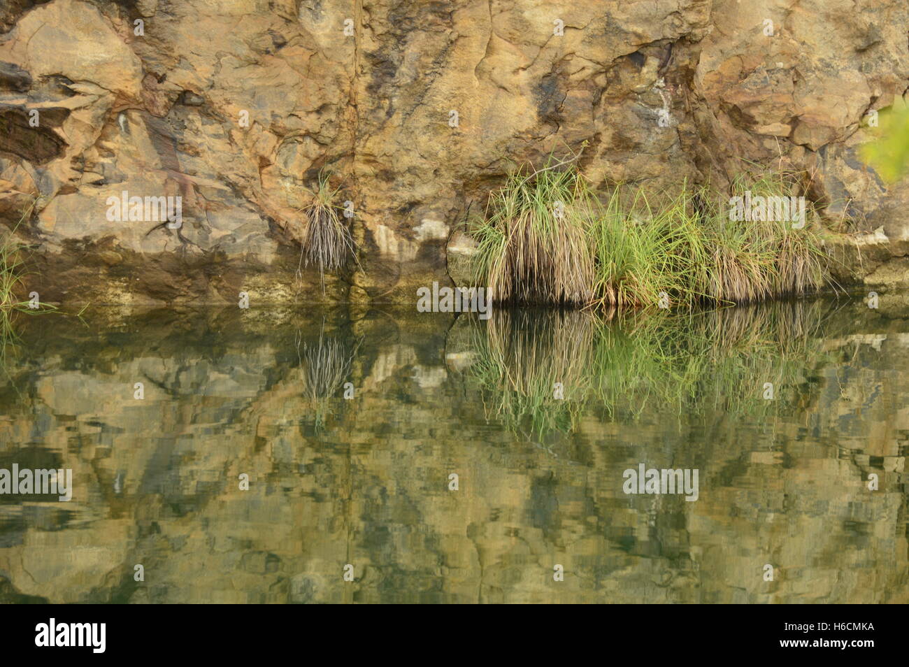 Rock wall reflected in lake water Stock Photo - Alamy