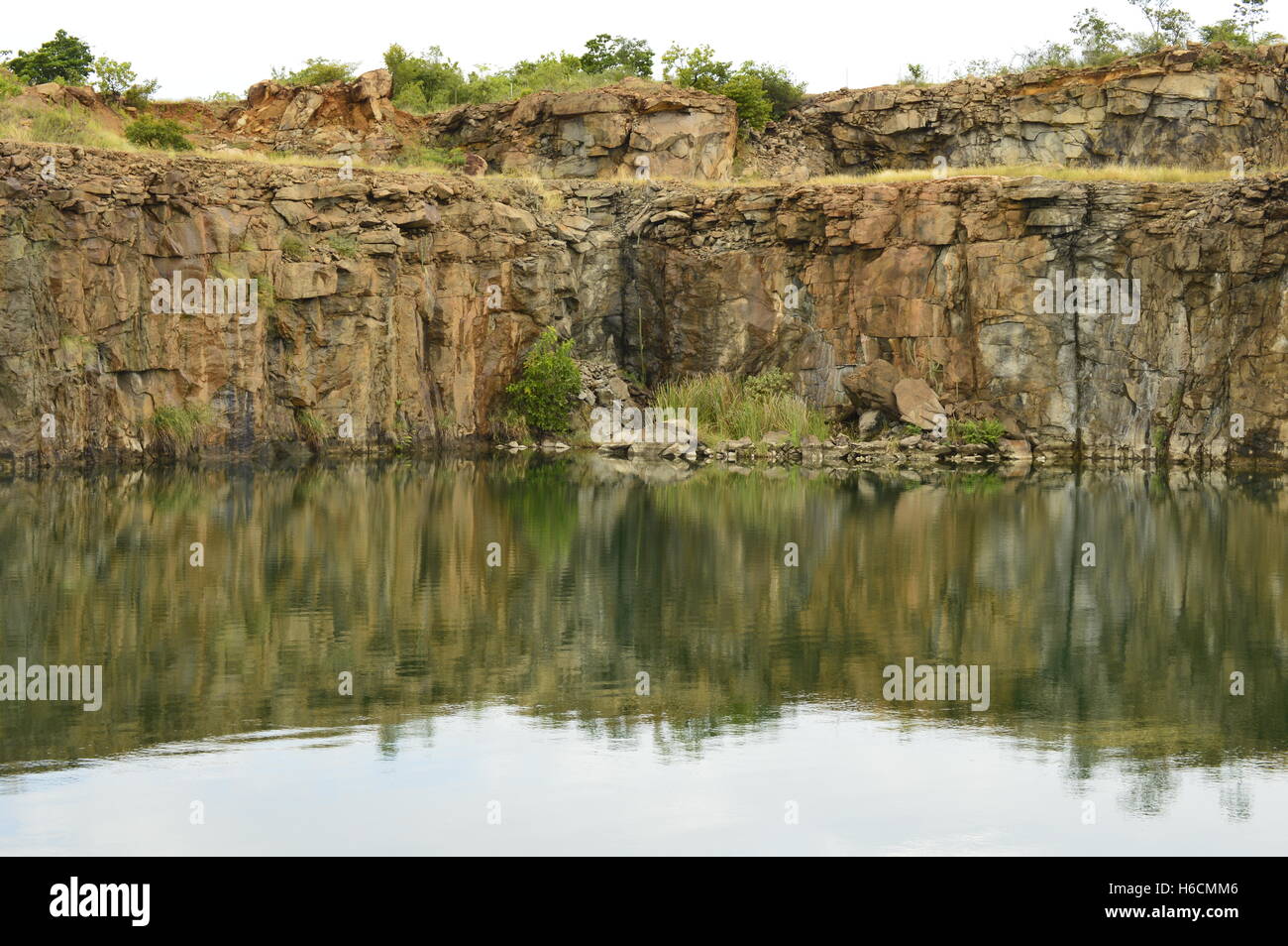Rock wall reflected in lake water Stock Photo - Alamy