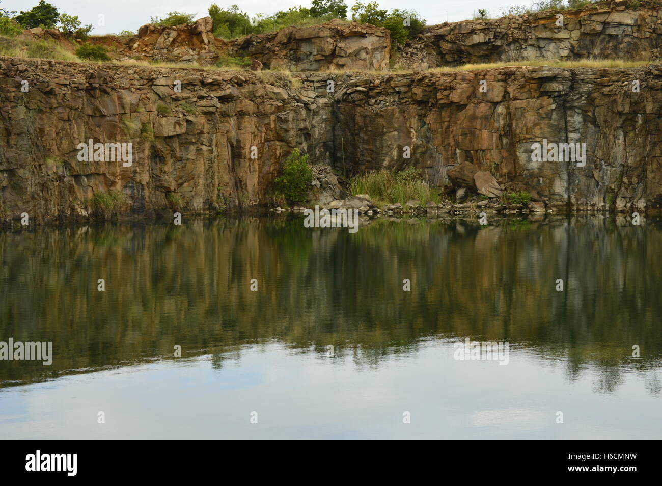 Rock wall reflected in lake water Stock Photo - Alamy