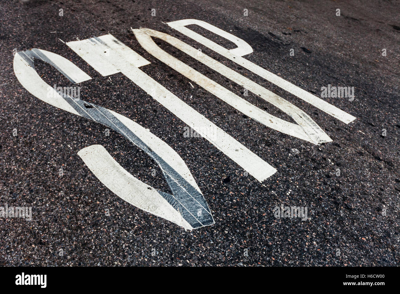 Wide angle view of a white painted "stop" side on a street's asphalt ...