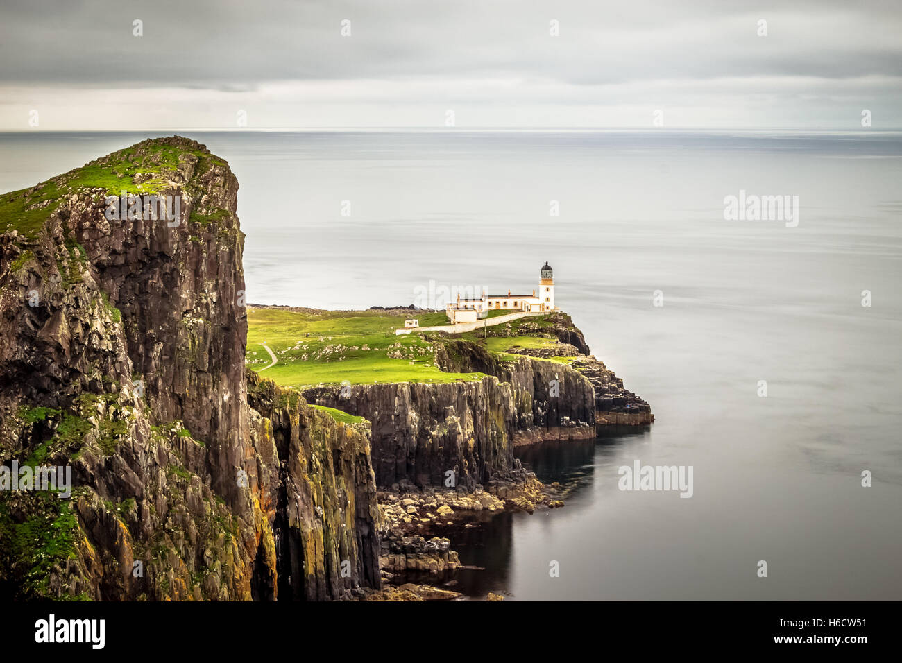Neist point lighthouse with a cliff to the right and dramatic clouds in ...