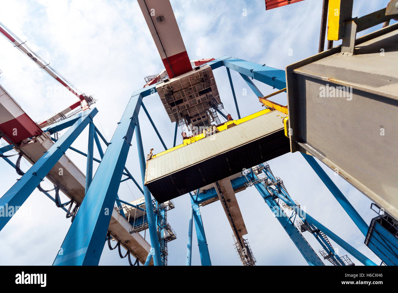 A massive freight crane transports a container from a truck onto a ...