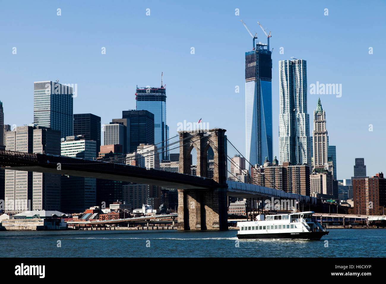 Ferry sailing on the East River with the Brooklyn Bridge stretching ...