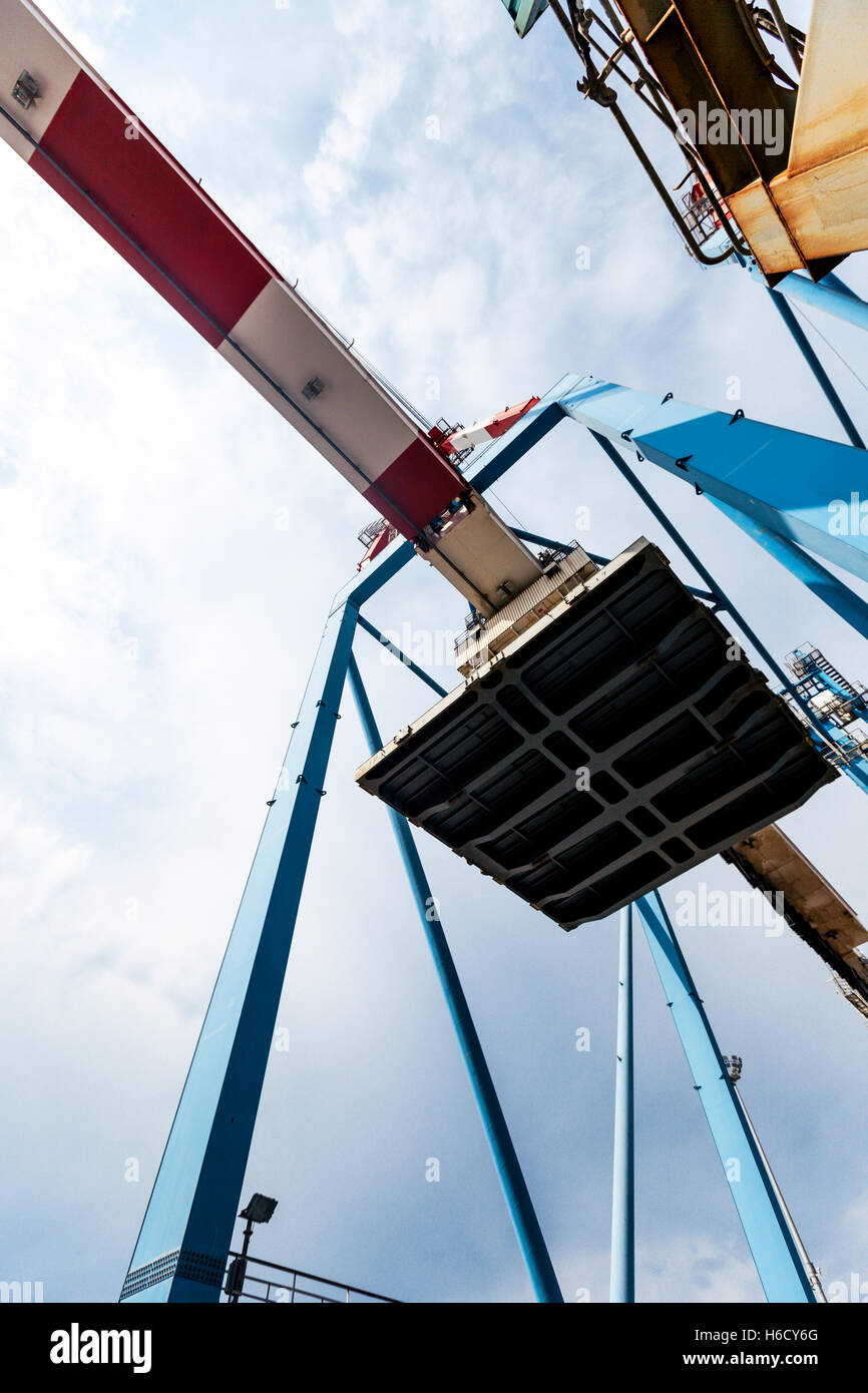 Low angle view of a harbor crane at work, loading a freighter ship with ...