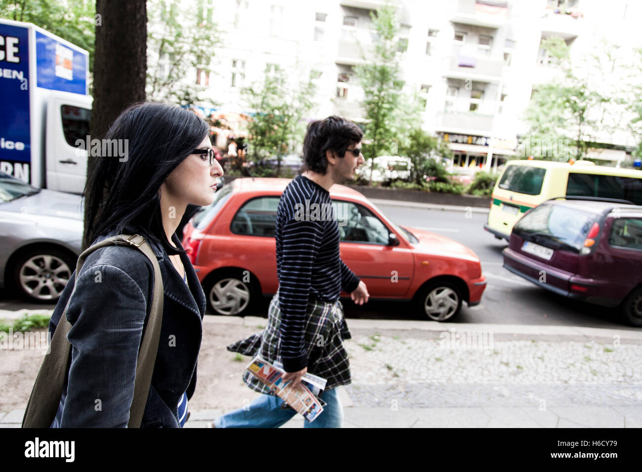 A couple in their early thirties crossing the street while having a ...