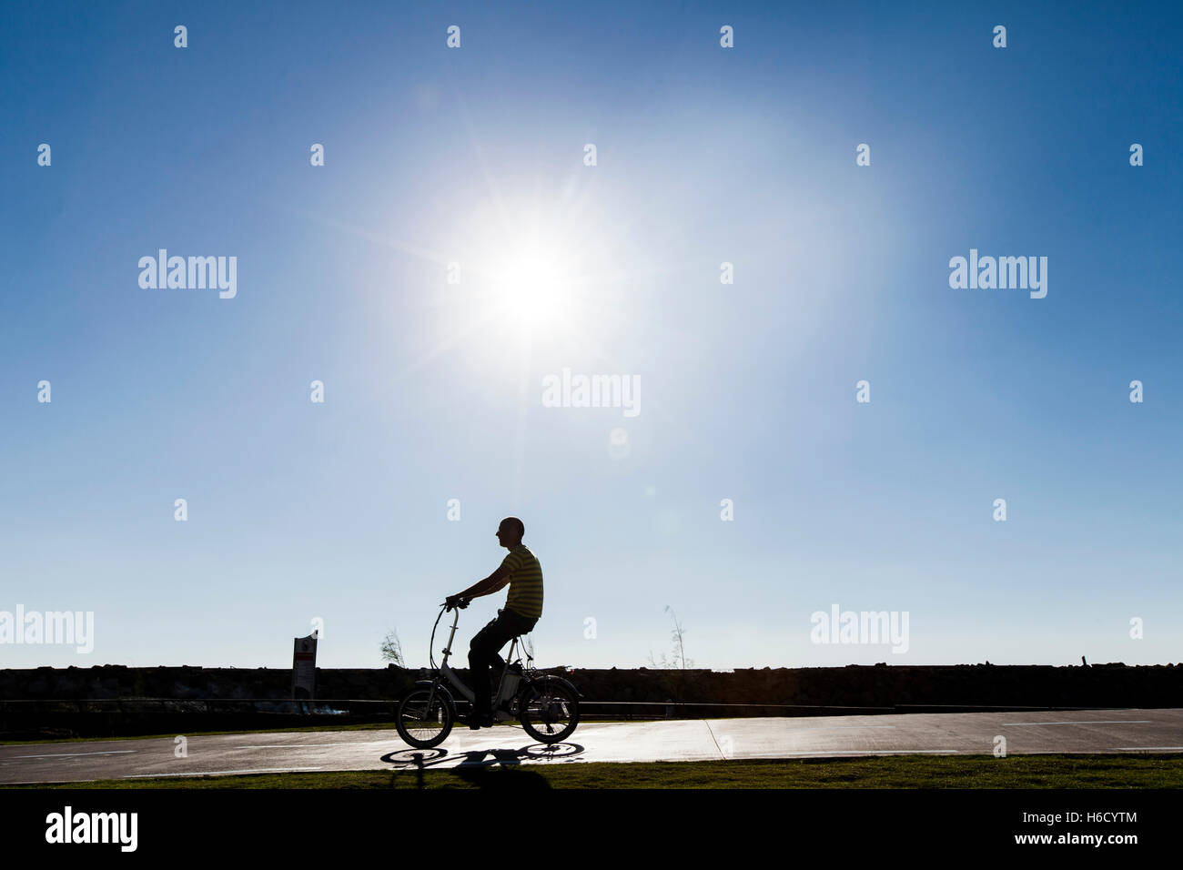 Silhouette of a cycler passing on a park path on a clear summer day ...