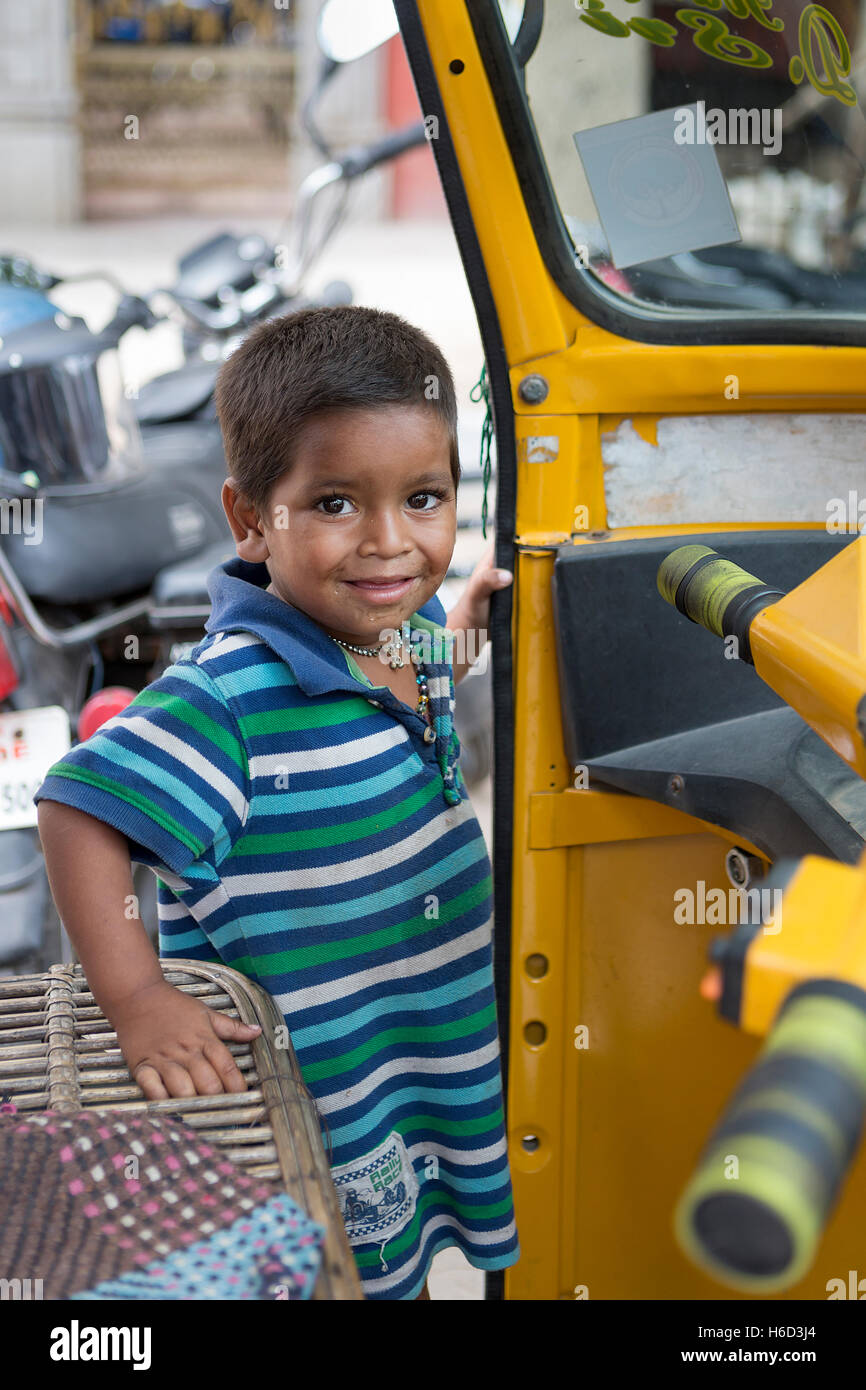Young Indian boy smiles at the camera from the other side of a Tuktuk ...