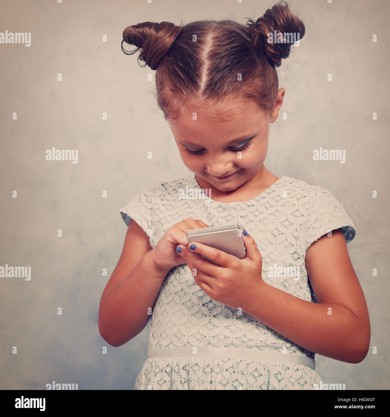 Cute kid girl with happy smile texting sms on mobile phone on blue ...