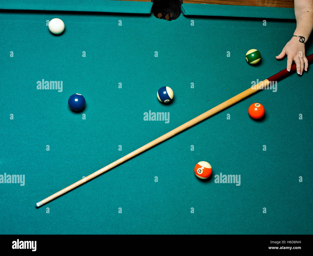 overhead view of womans hand reaching for pool cue on pool table Stock ...