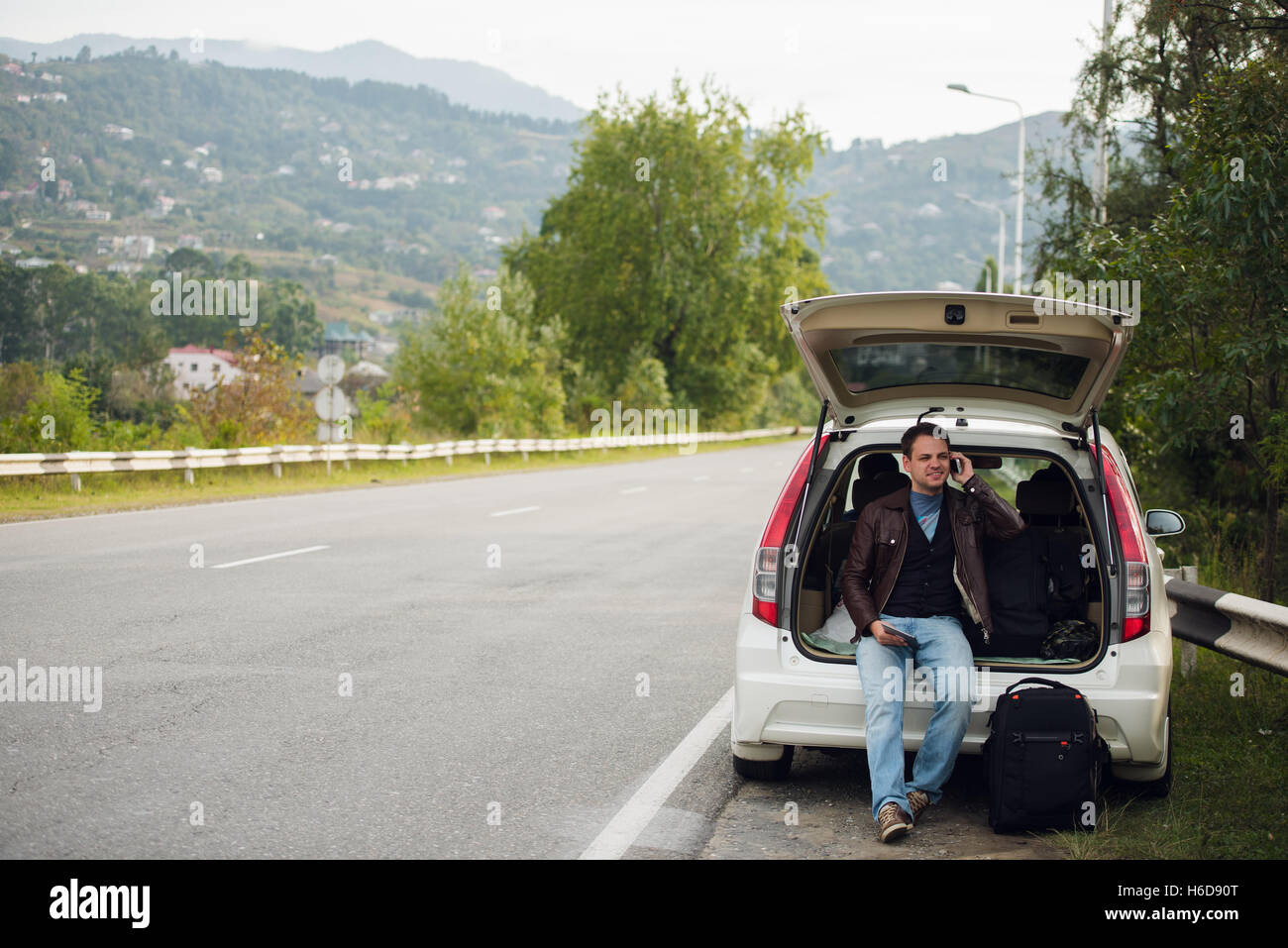 Calling friends. Happy young man talking mobile phone and sitting on a ...