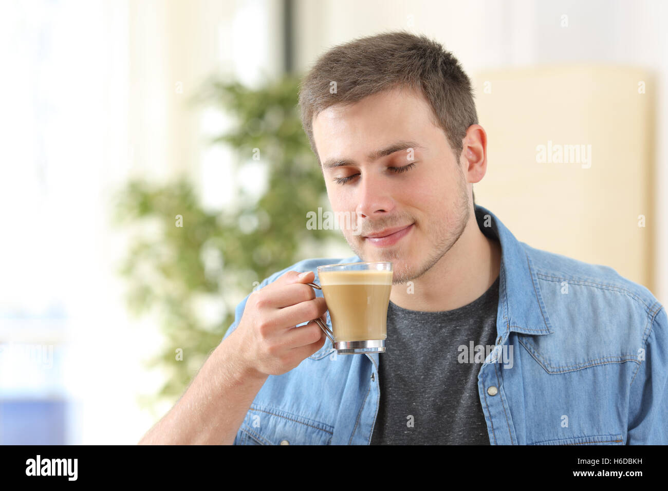 Man tasting coffee with milk and smelling its aroma at home Stock Photo ...